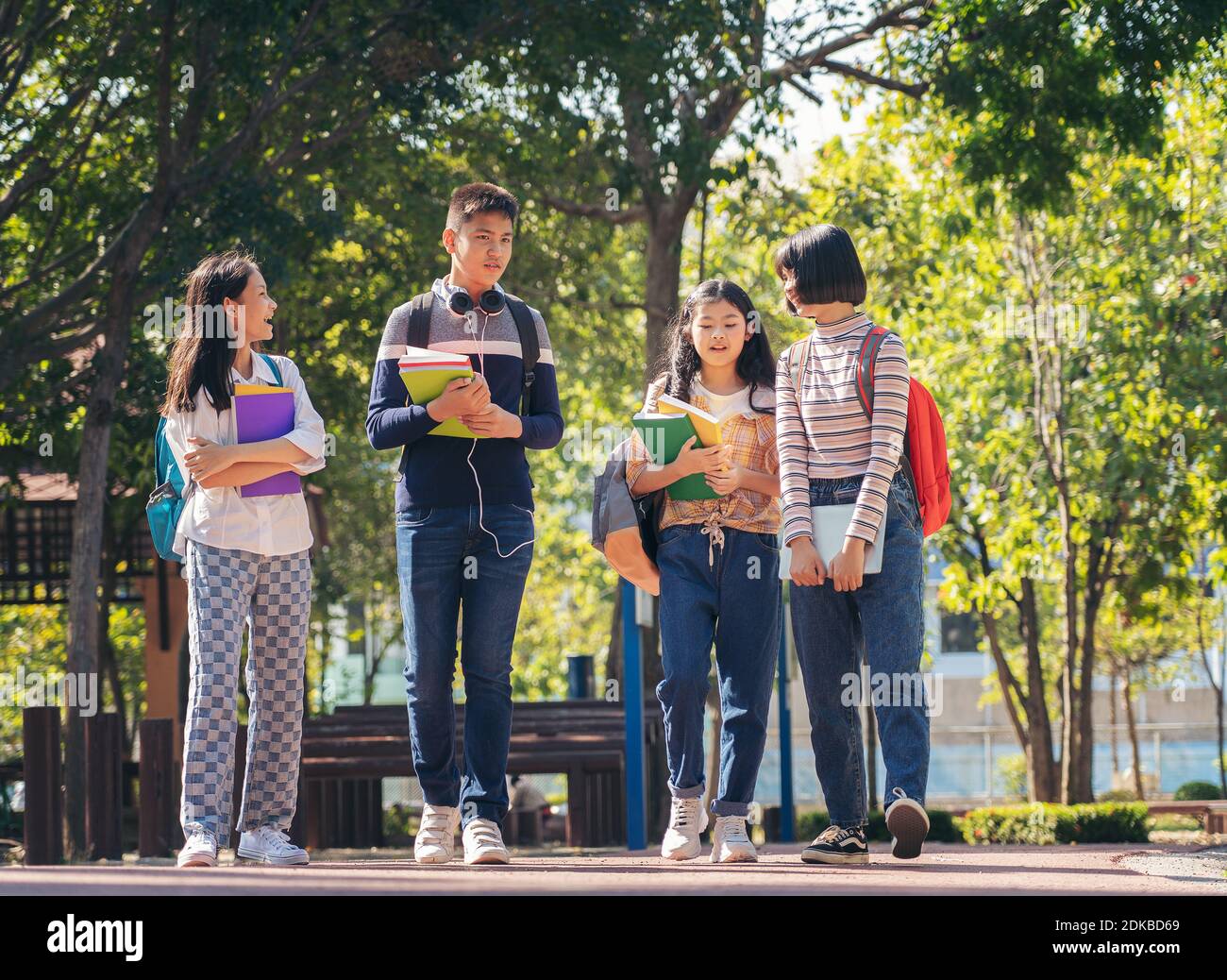 Girls And Boy Walking With Book On Footpath Stock Photo - Alamy