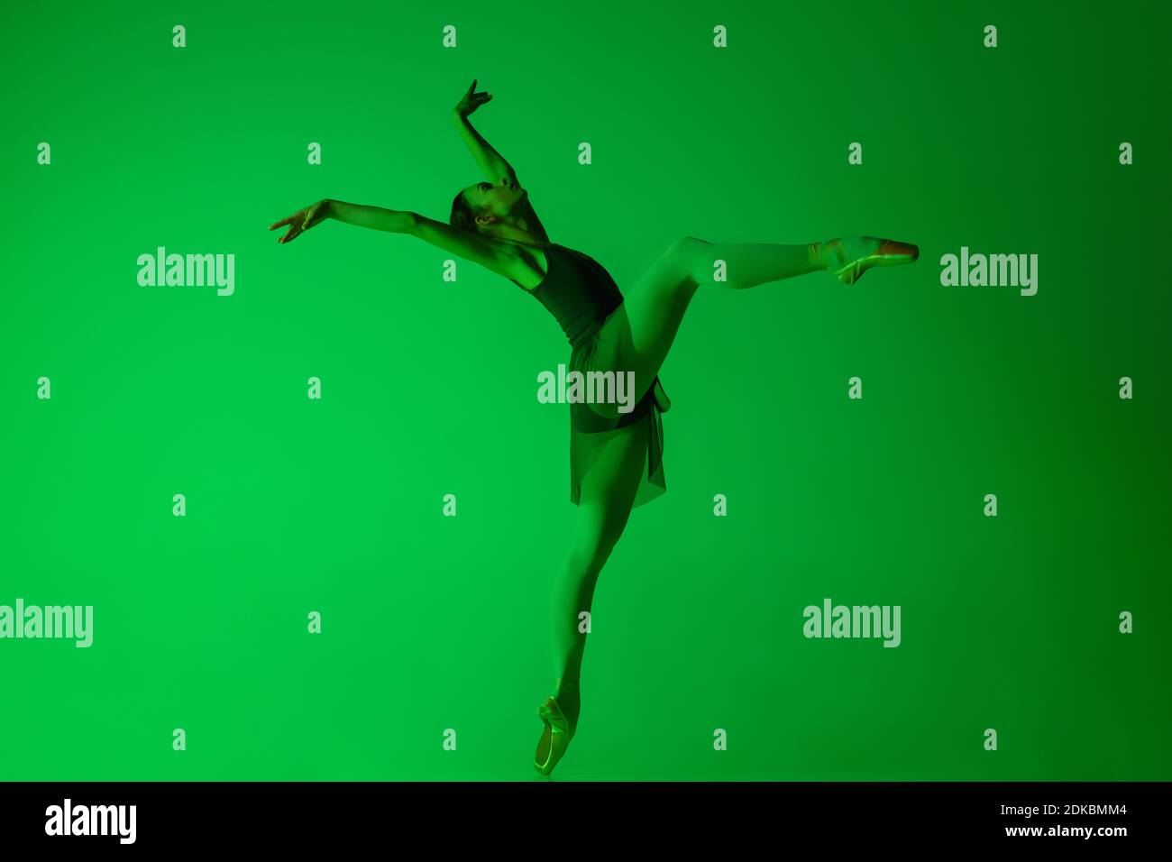 Attention. Young and graceful ballet dancer isolated on gradient green ...