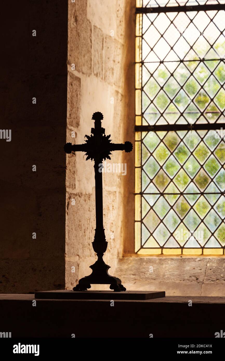 Cross silhouette on altar near window in dark empty old chapel. Game of ...