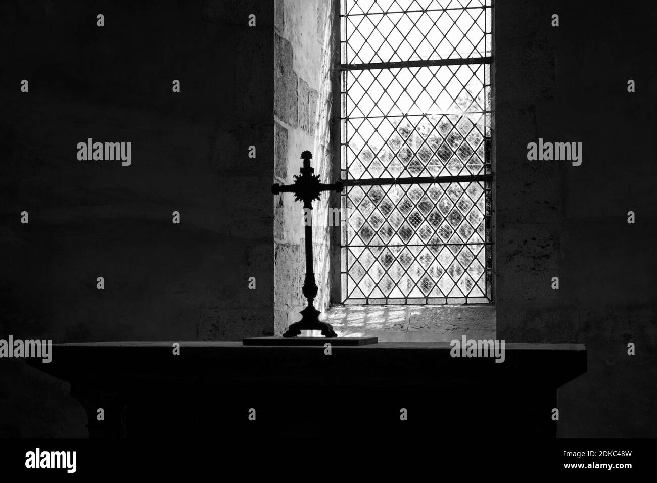 Cross silhouette on altar near window in dark empty old chapel. Game of ...
