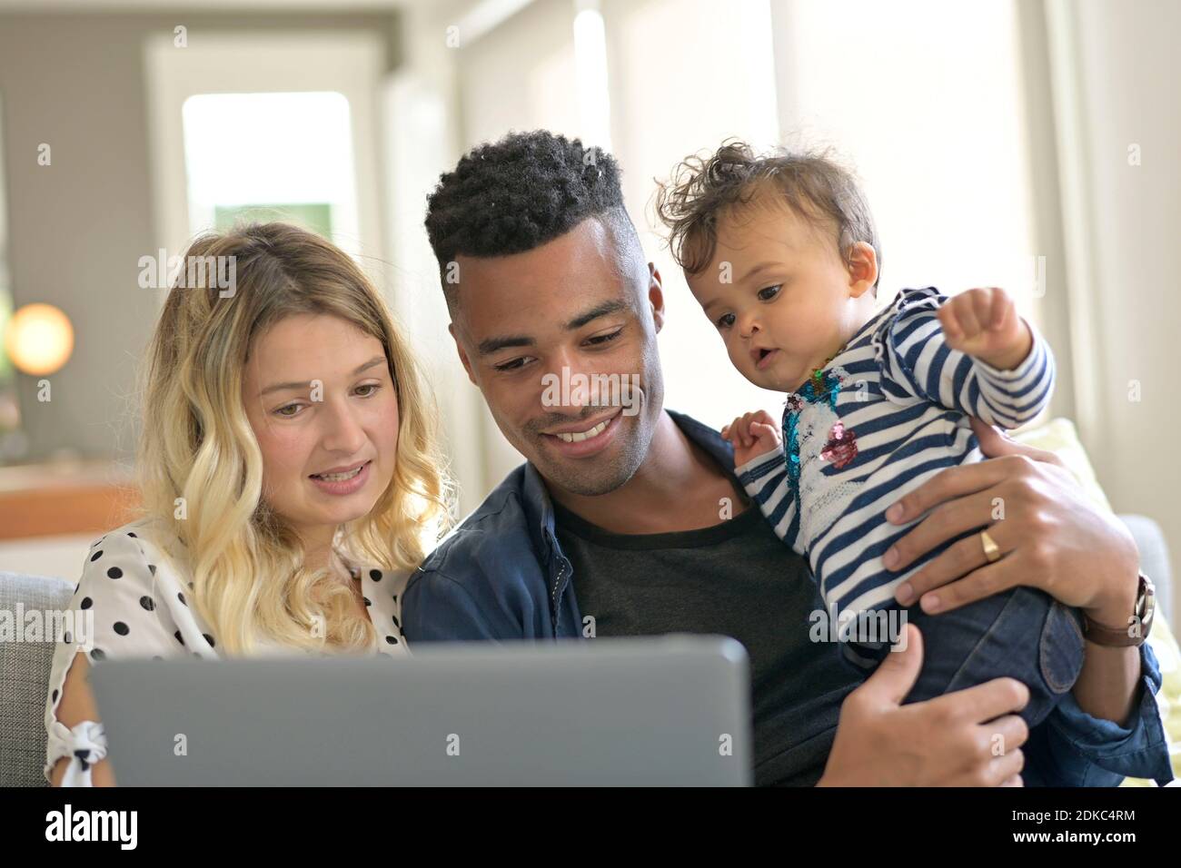 Parents with baby girl using laptop computer at home Stock Photo - Alamy
