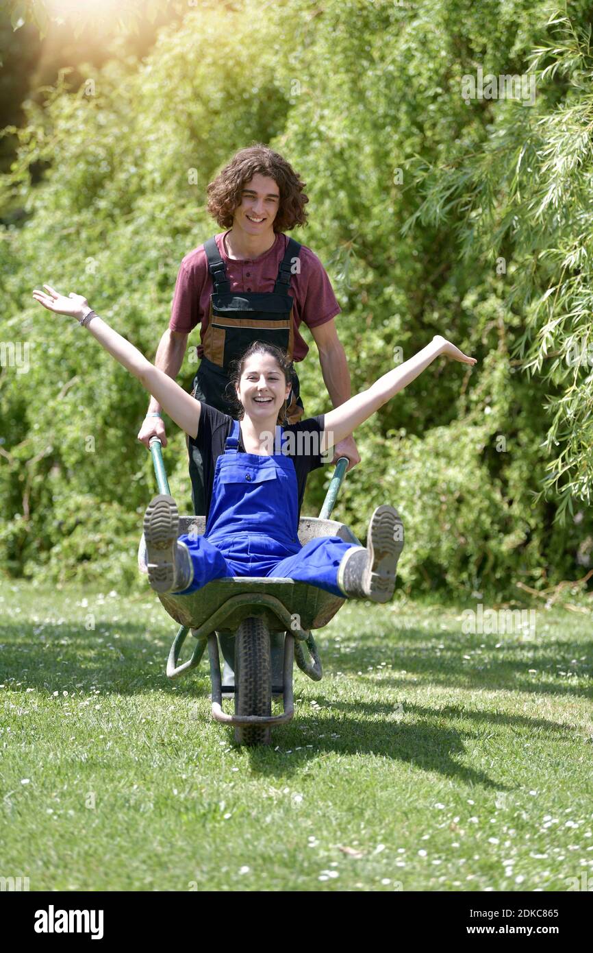 Young people having fun in yard, playing with wheelbarrow Stock Photo ...