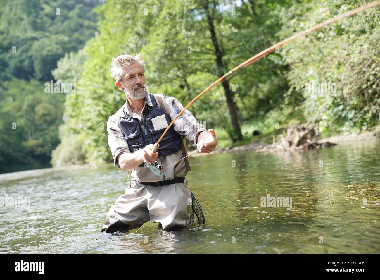 Man fly fishing in the summer in a beautiful river with clear water ...