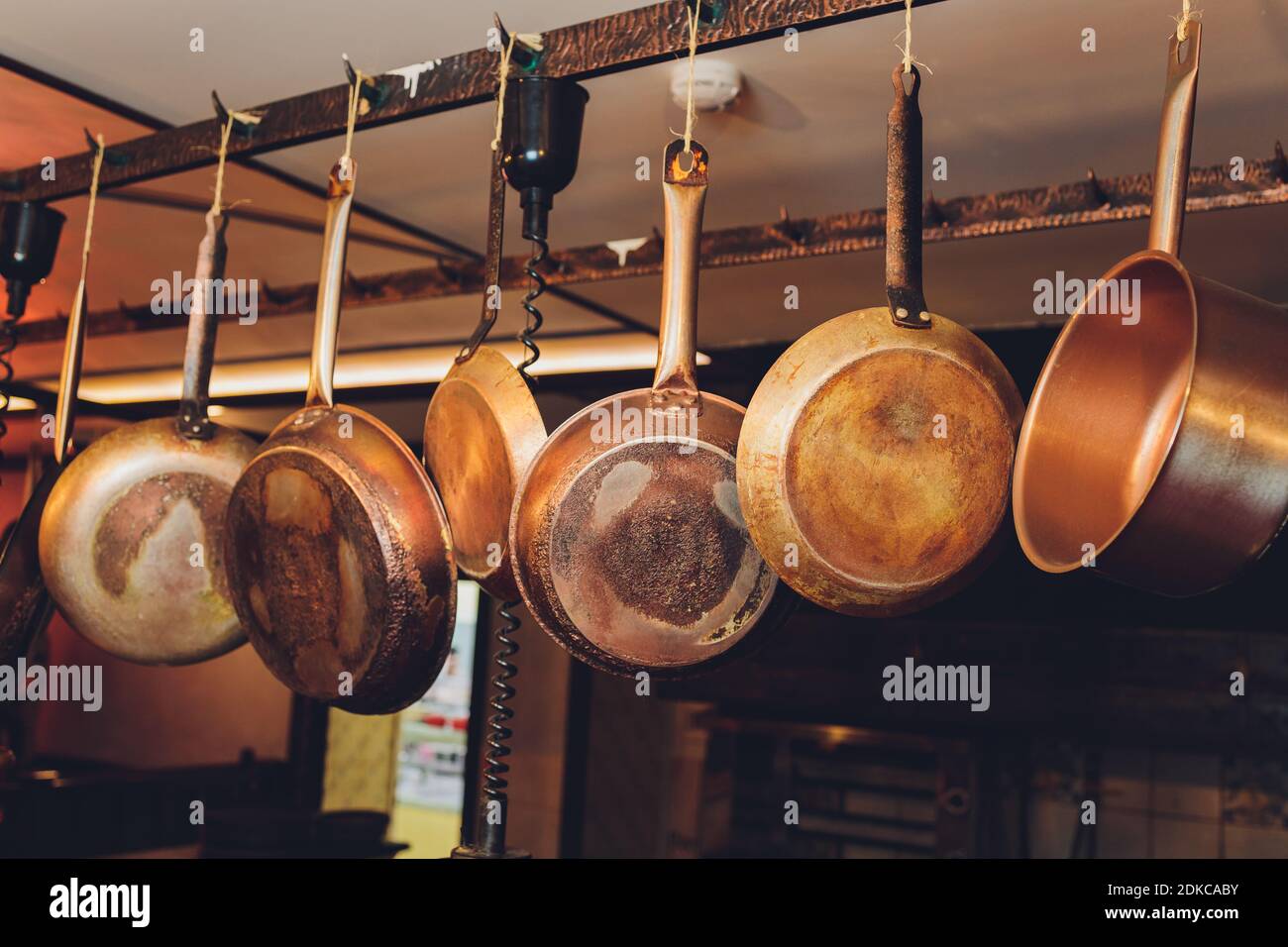 Old kitchen pans hanging on the bar. Different size of pans on the wall ...