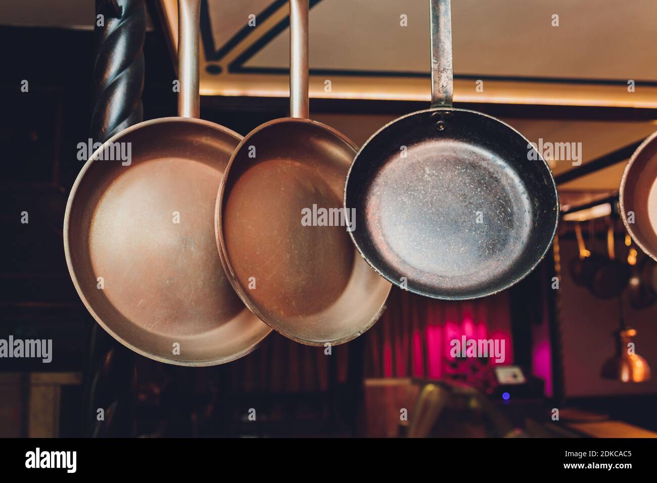 Old kitchen pans hanging on the bar. Different size of pans on the wall ...