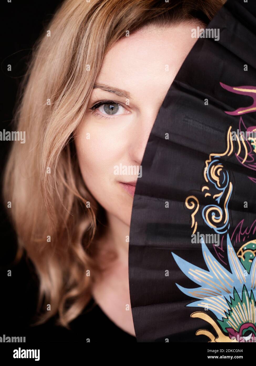 Beautiful woman with face partially hidden behind oriental fan Stock ...