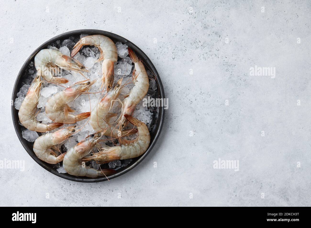 Fresh tiger prawns in plate with ice on white textured background, top ...