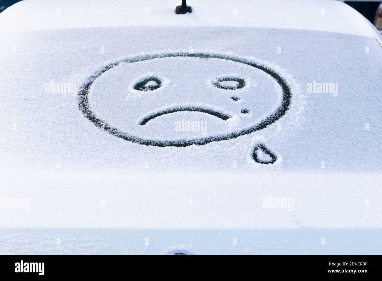 image of a crying face emoji on the snow on the back window of a car on ...