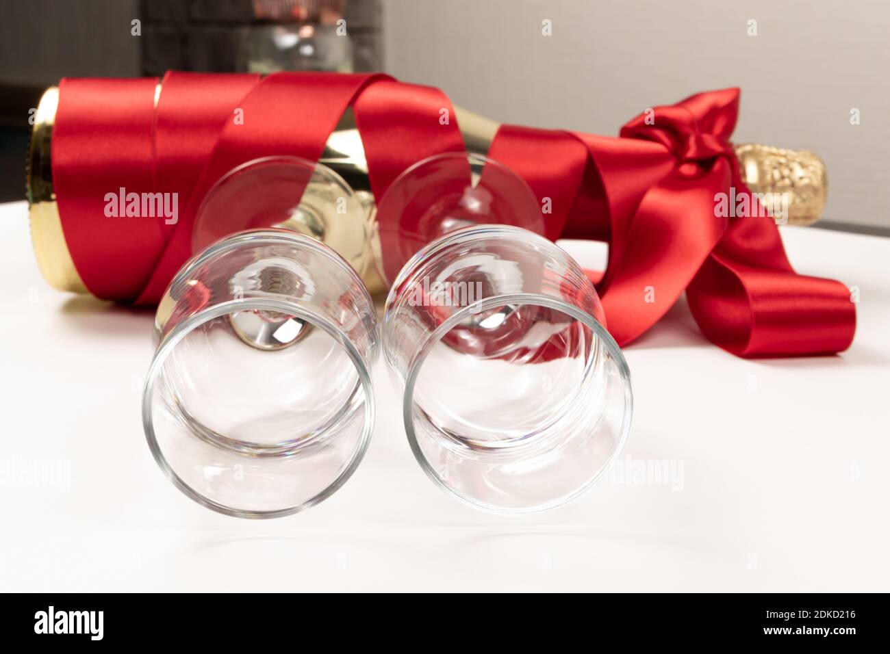 two empty glasses close up and a gift bottle of champagne wrapped in a ...