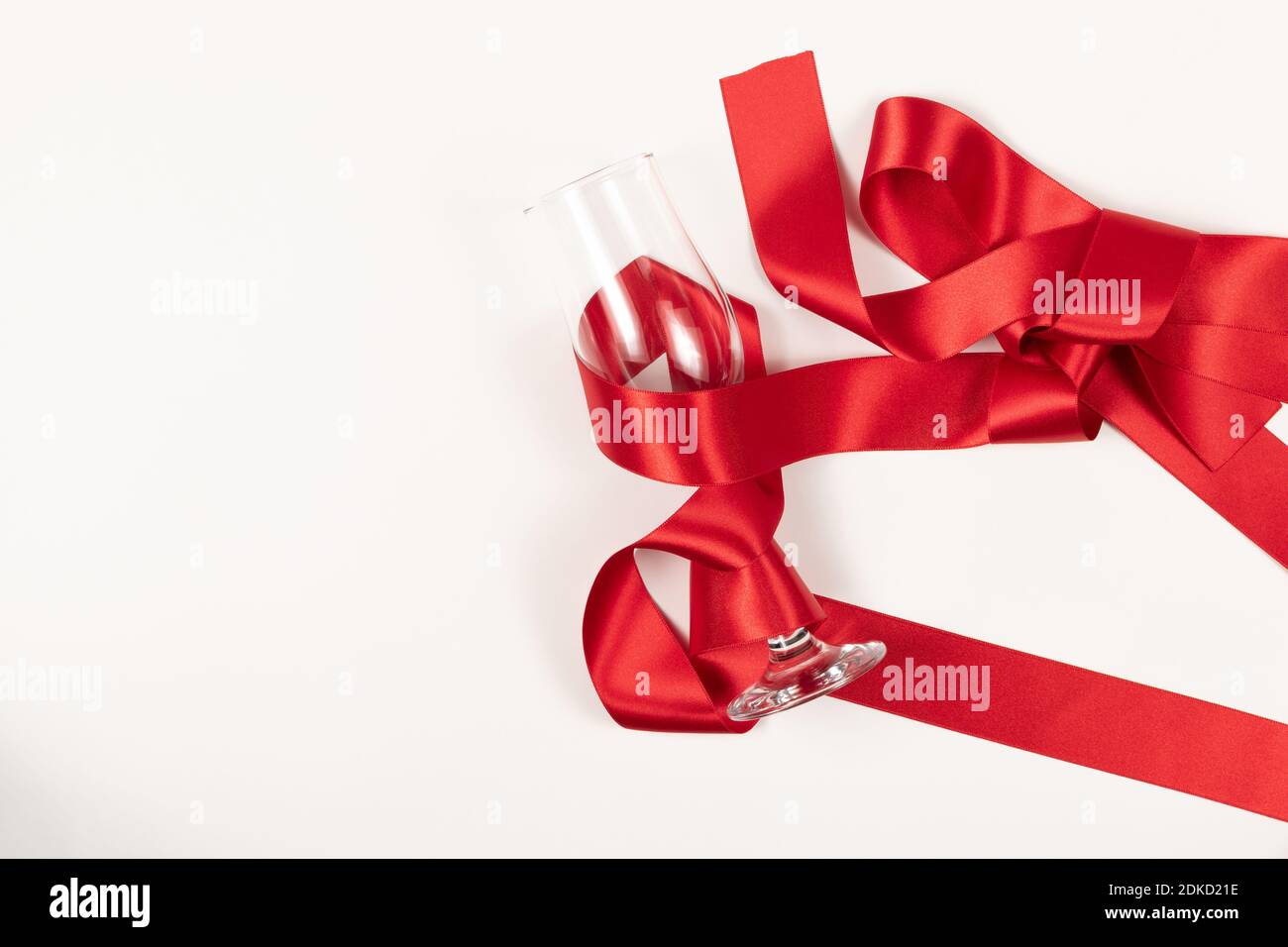 a glass wrapped in a red satin ribbon close-up lies on a white ...