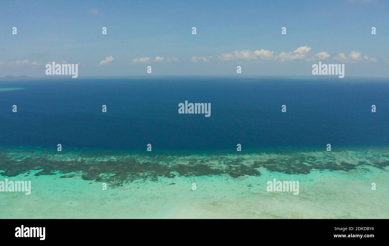 Tropical coral atoll with turquoise water against the sky with clouds ...