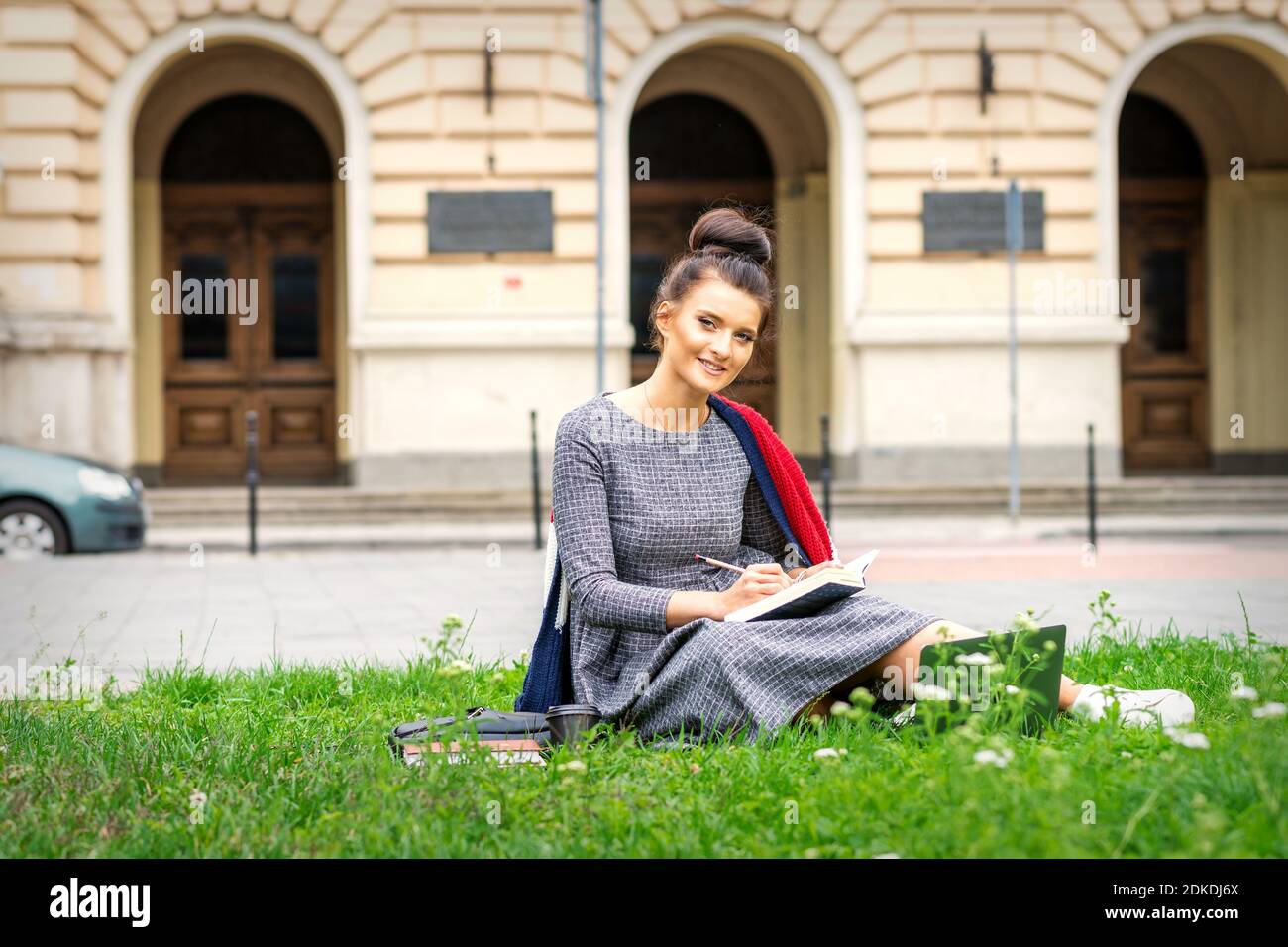 Portrait of a beautiful young smiling student studying with a book on ...