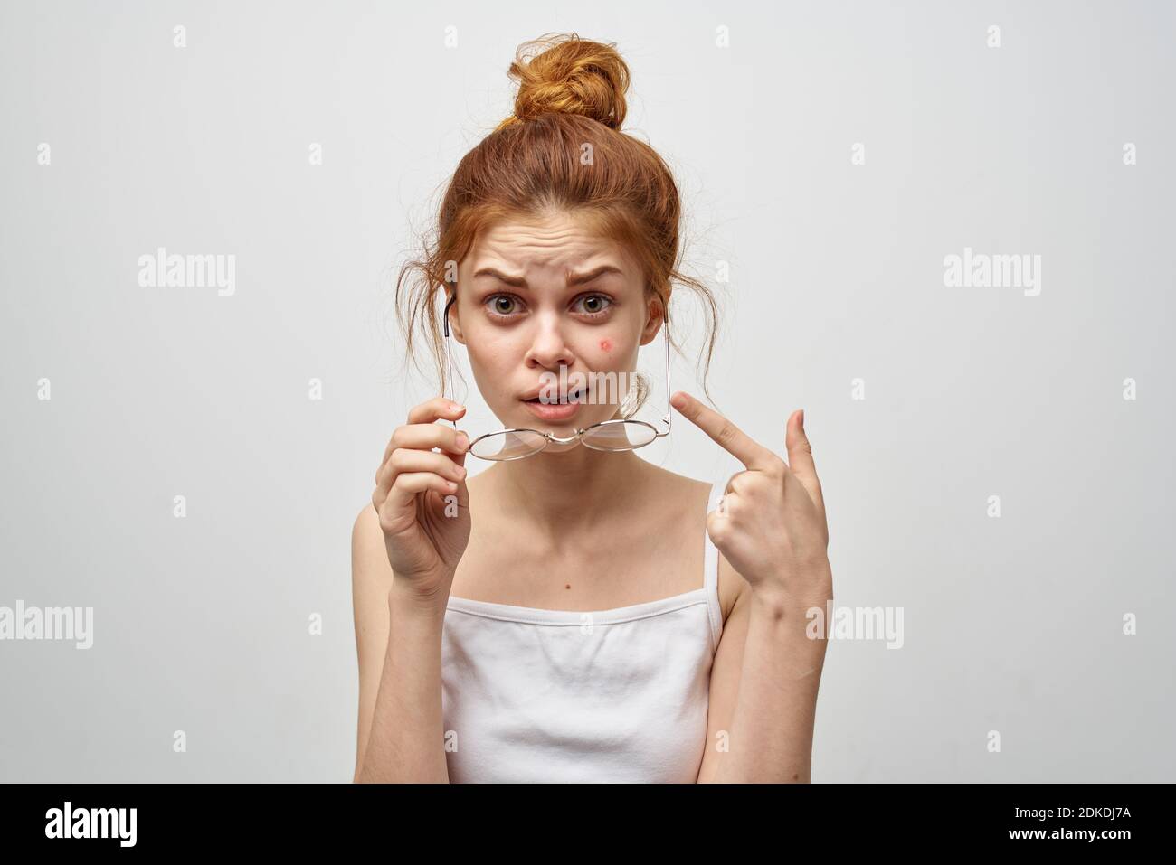 woman with glasses shows a finger to a red pimple on her face health ...