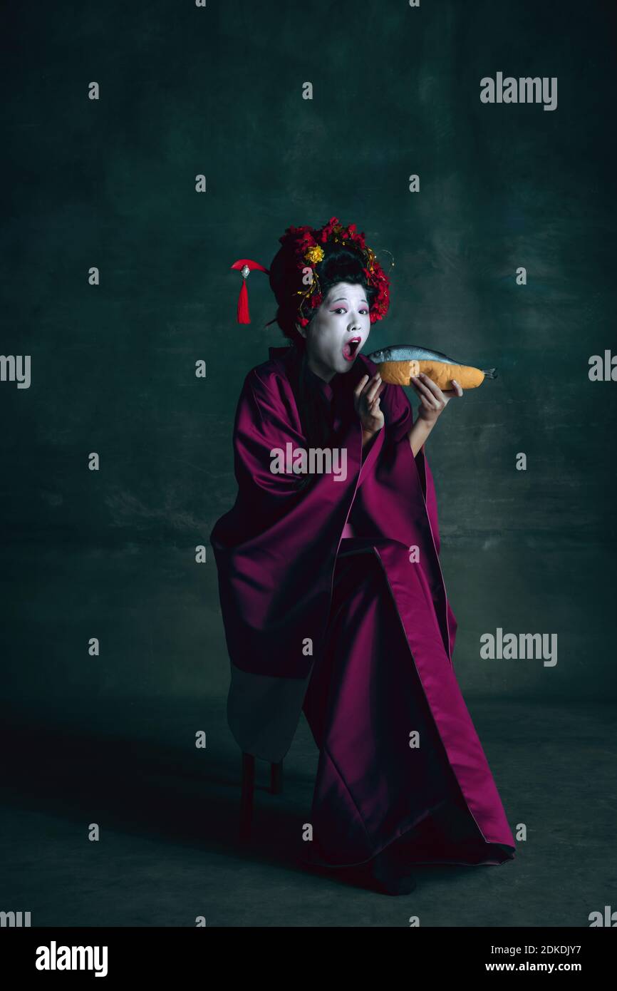 No diet with hot-dog. Young japanese woman as geisha isolated on dark ...