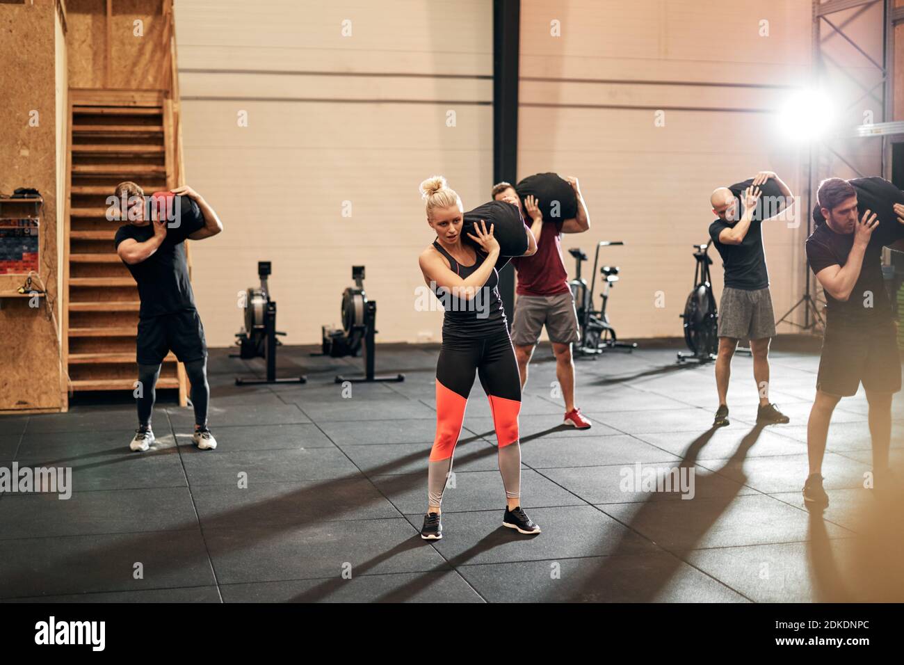 Fit group of people working out with weight bags during a strengthening ...
