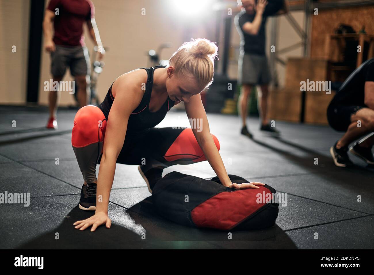 Fit young woman in sportswear looking exhausted after an exercise class ...
