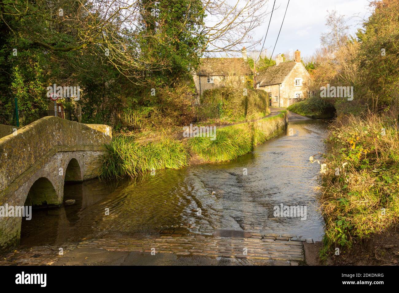 Stream flowing in ford road after winter rain, village street with ...