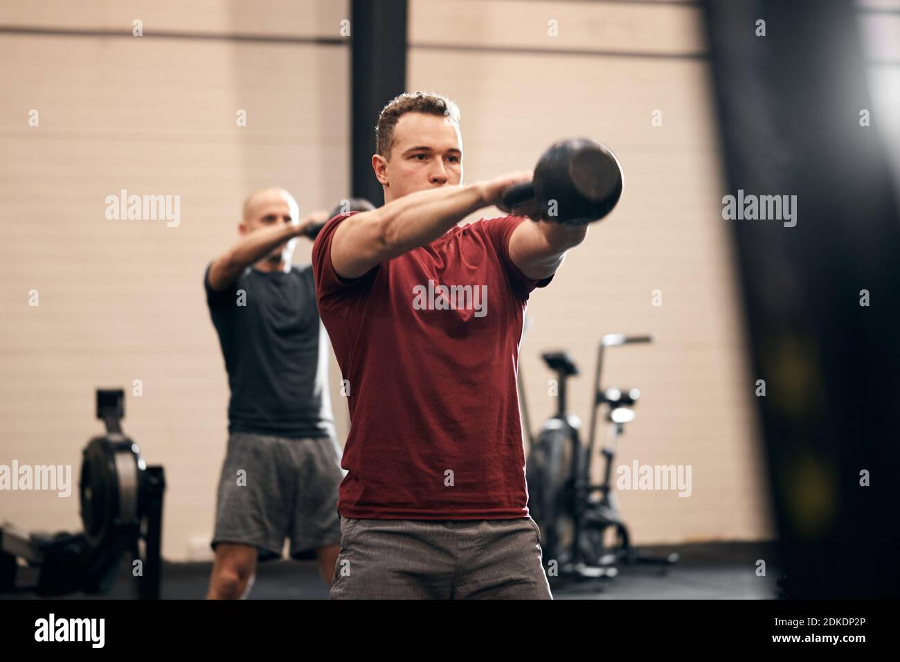 Fit young man in sportswear swinging a weight during a strength ...