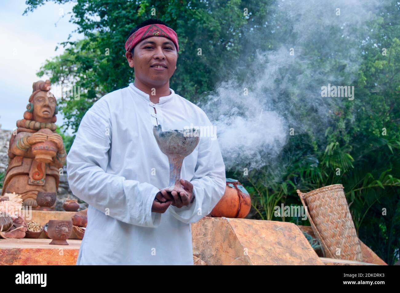 Young Mayan man in a ceremony, with a lit brazier in his hands. In the ...
