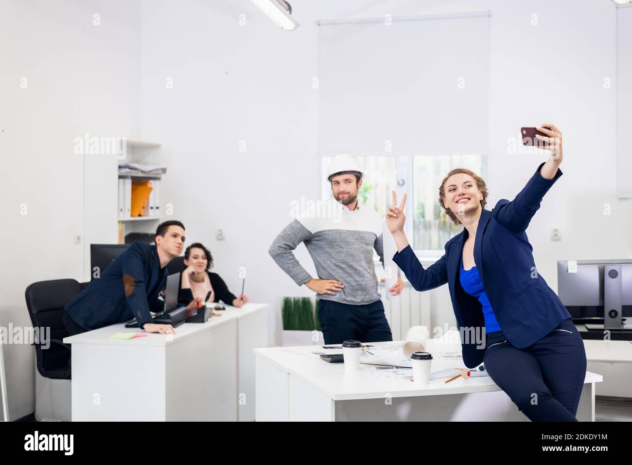 Employees having fun in the office, posing and taking selfies with a ...
