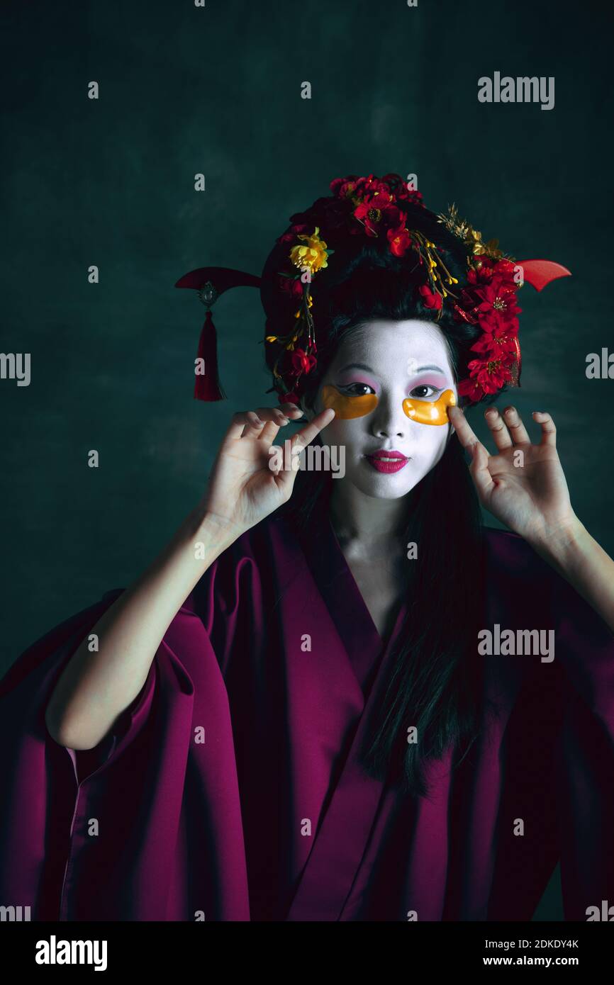 Eye patches. Young japanese woman as geisha isolated on dark green ...
