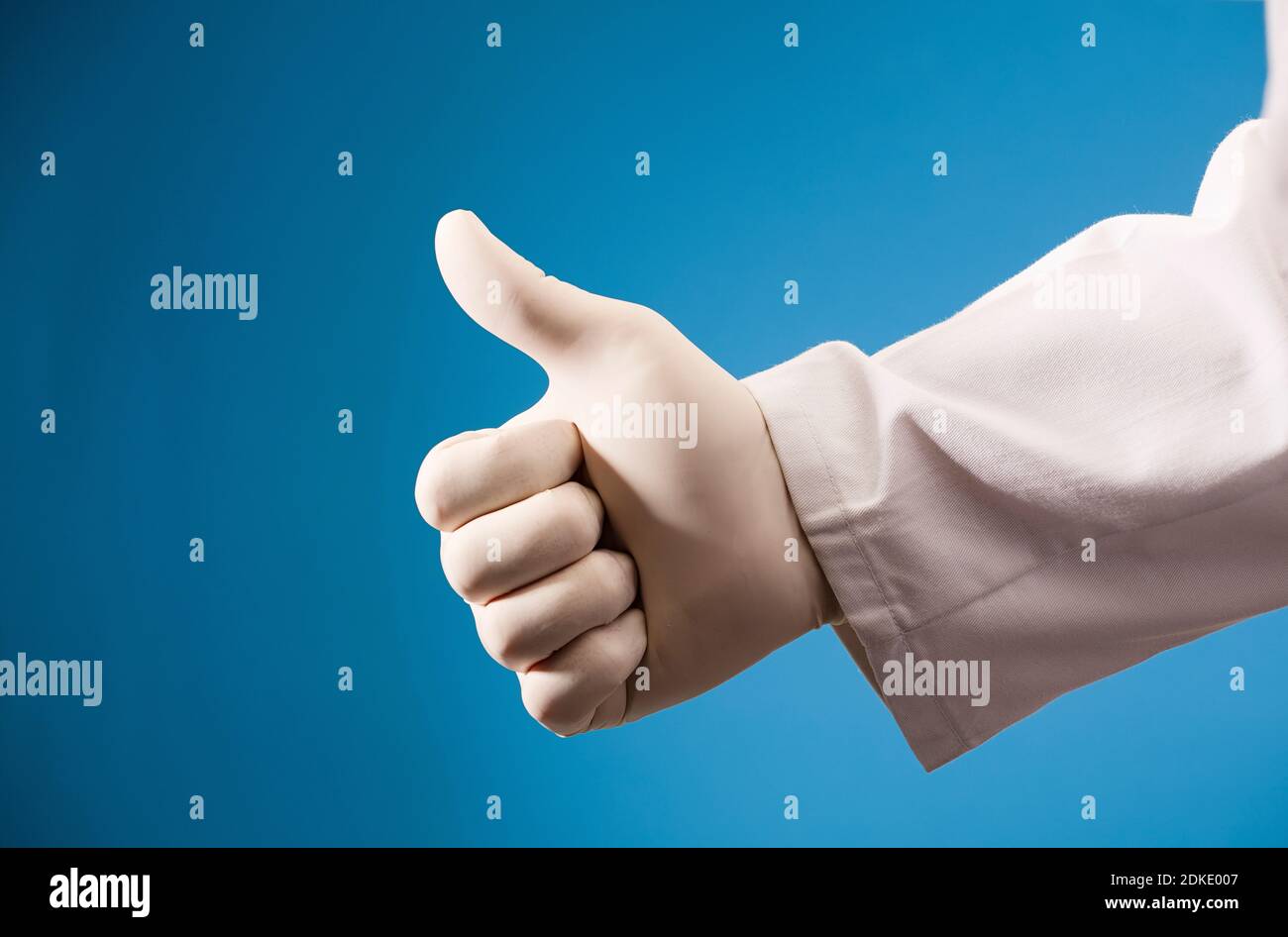 hand of doctor doing ok symbol, with surgical glove and blue background ...