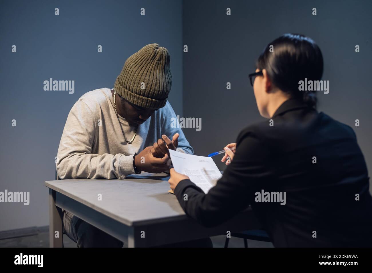 At the police station, a girl investigator interrogates a black guy who ...