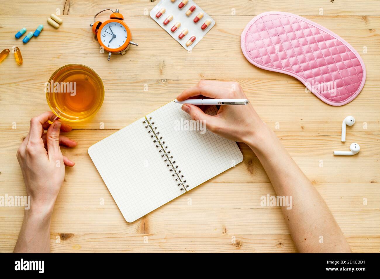 Female hand write in notebook - day plan before sleeping. Top view ...
