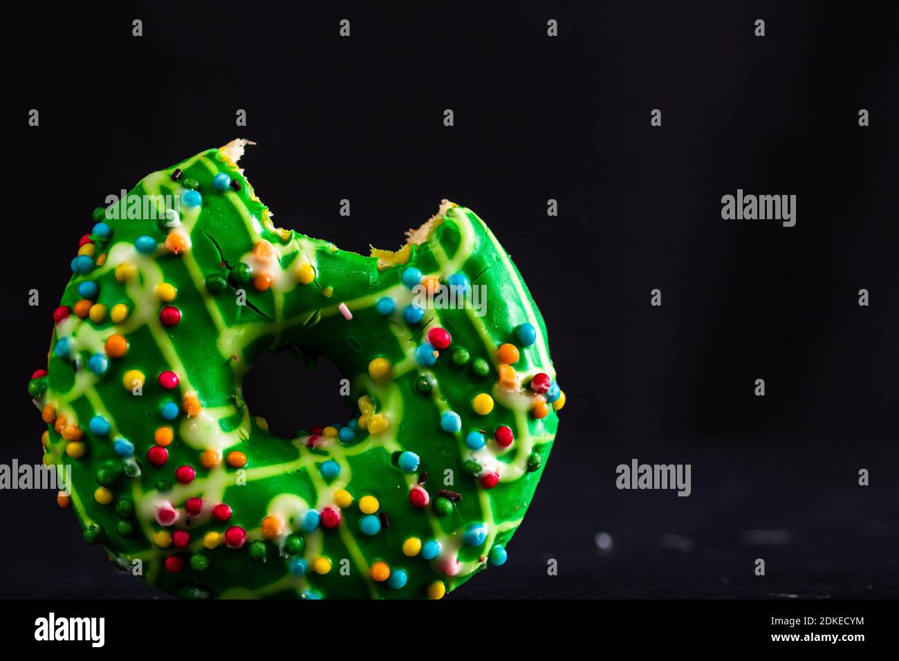 Green glazed donut with sprinkles isolated. Close up of colorful bitten donut Stock Photo - Alamy