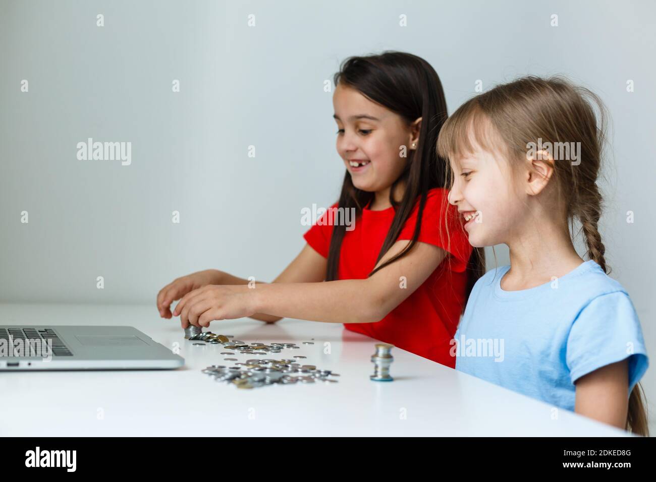portrait of little girls sitting at table and calculating money Stock ...