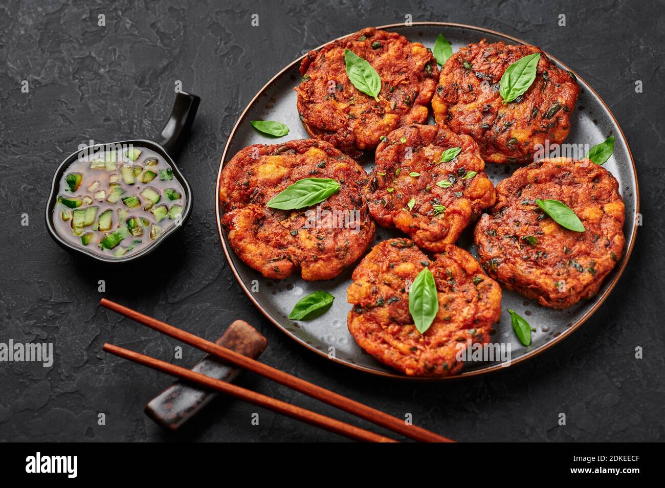 Tod Mun Pla or Thai Fish Cakes on black plate on dark slate table top ...