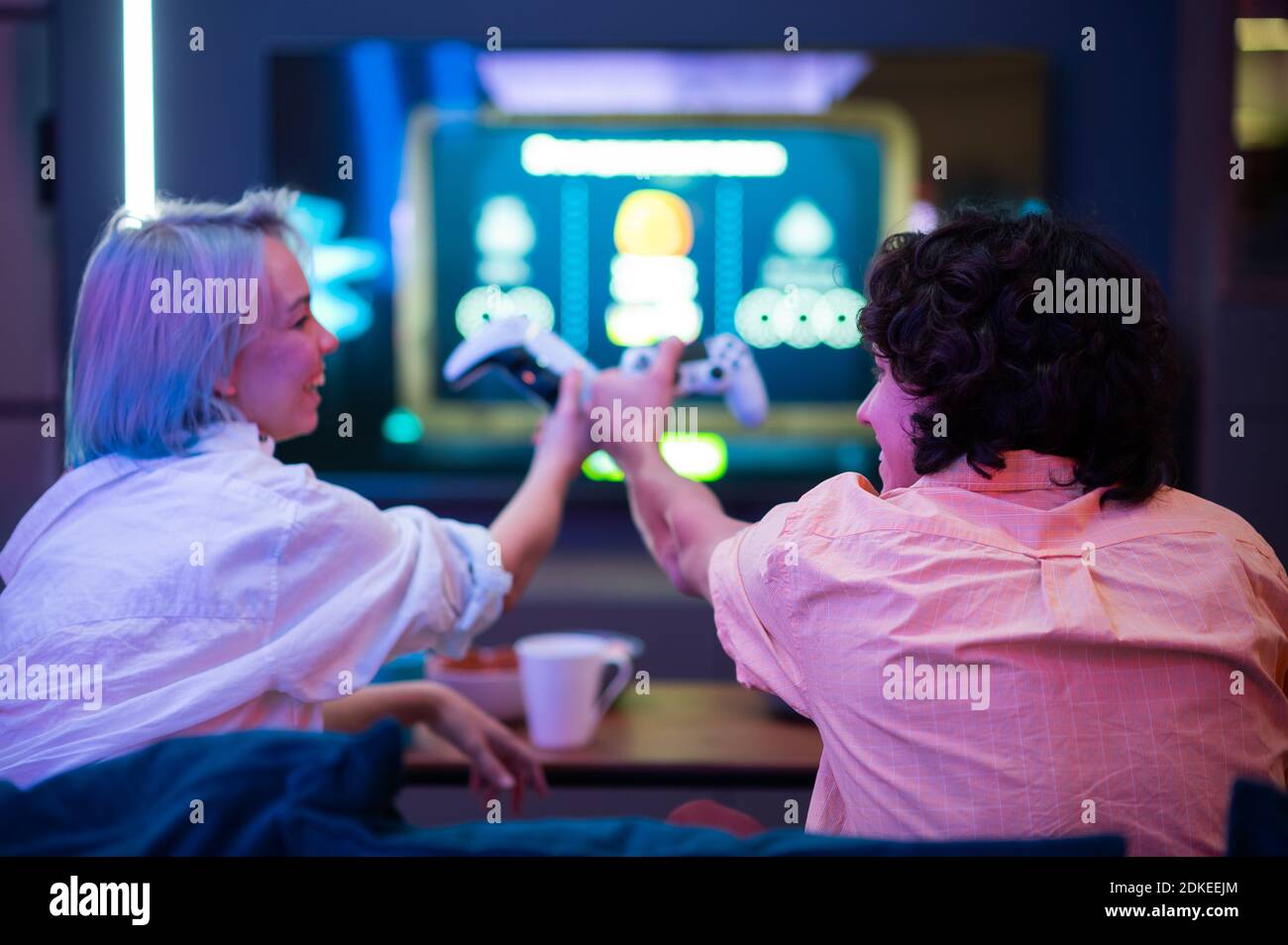 Happy couple playing video games at home during self isolation on a ...