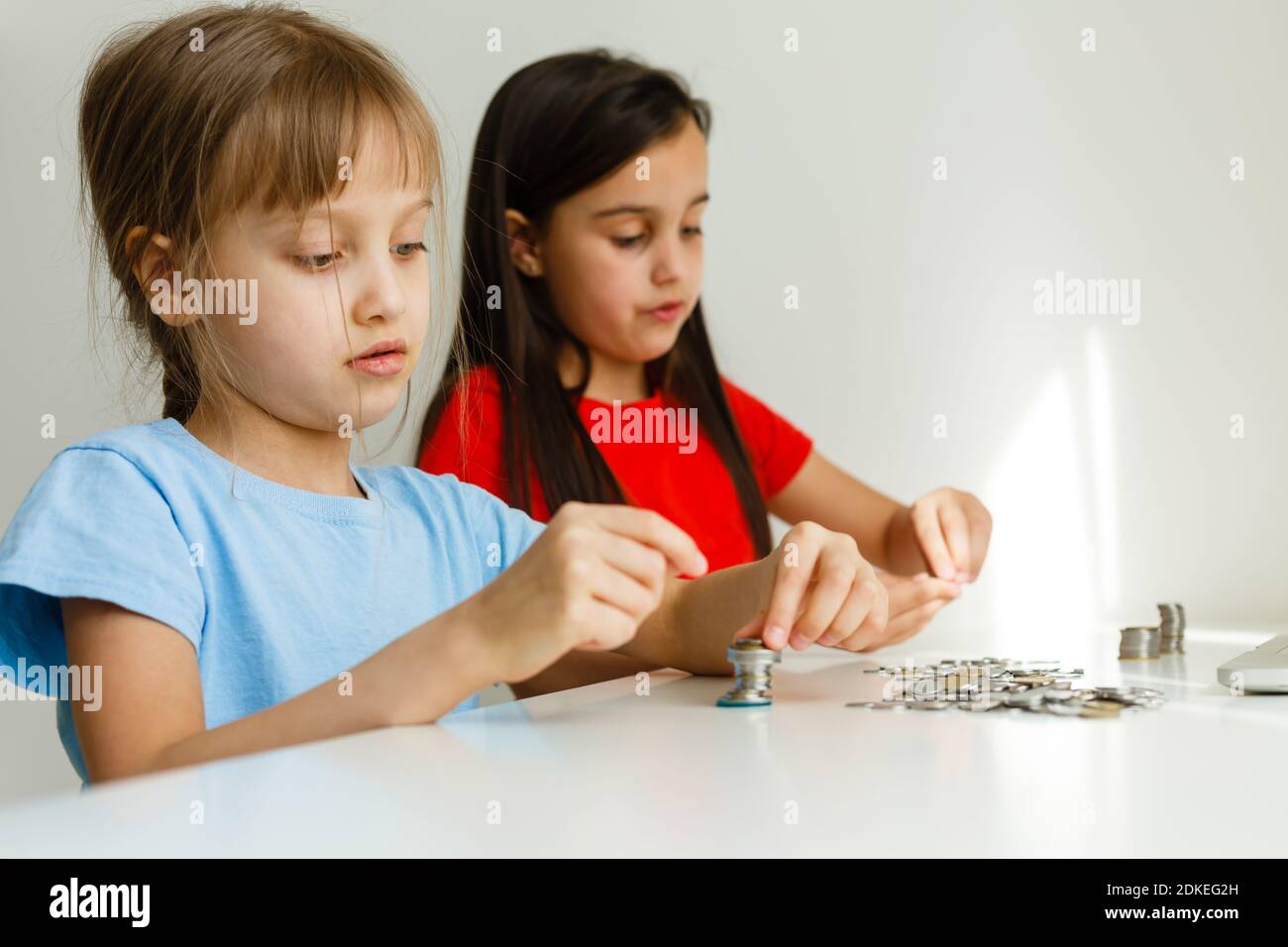 portrait of little girls sitting at table and calculating money Stock ...