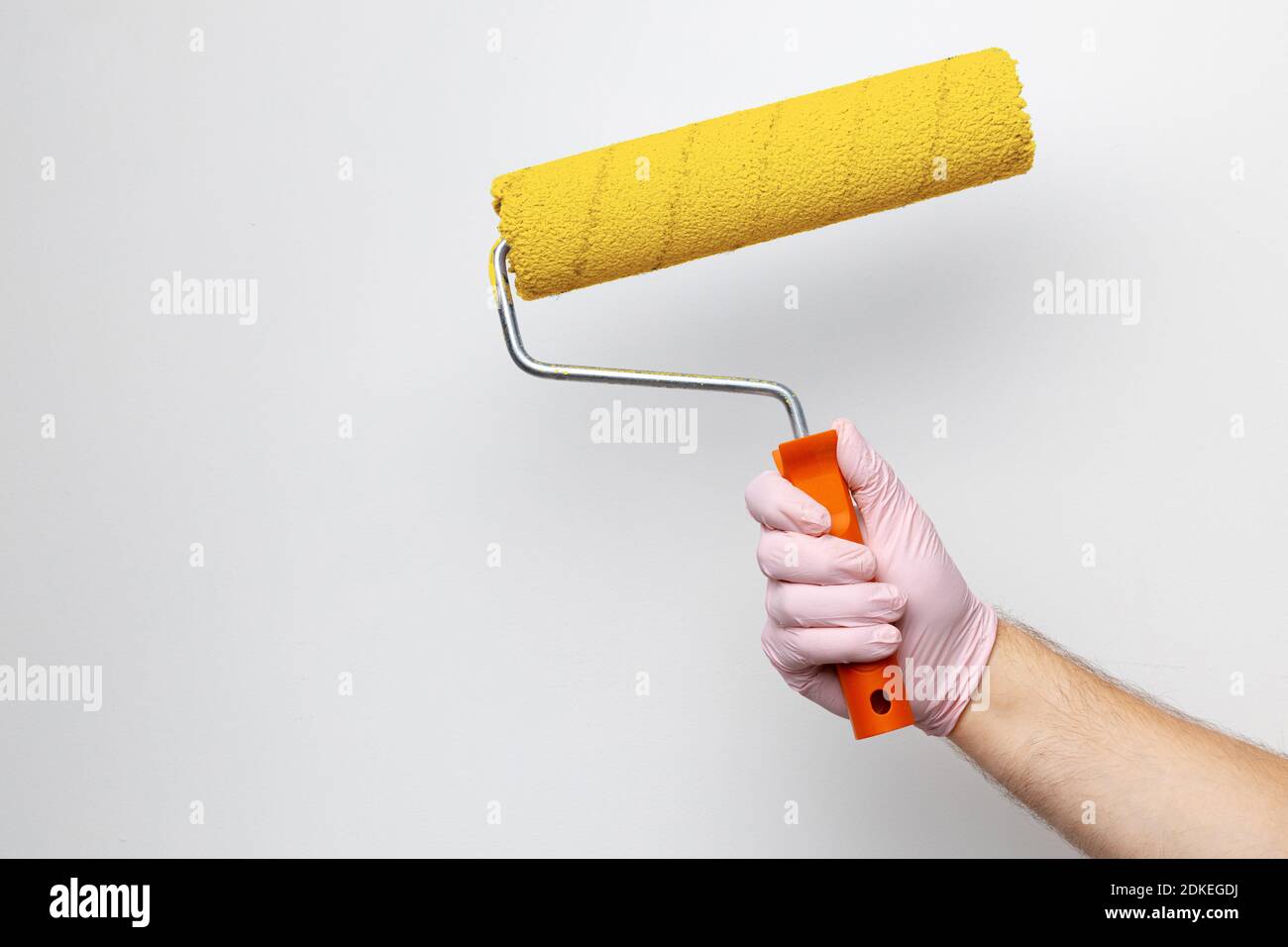 Gloved male hand painting wall into Illuminating yellow color Stock ...