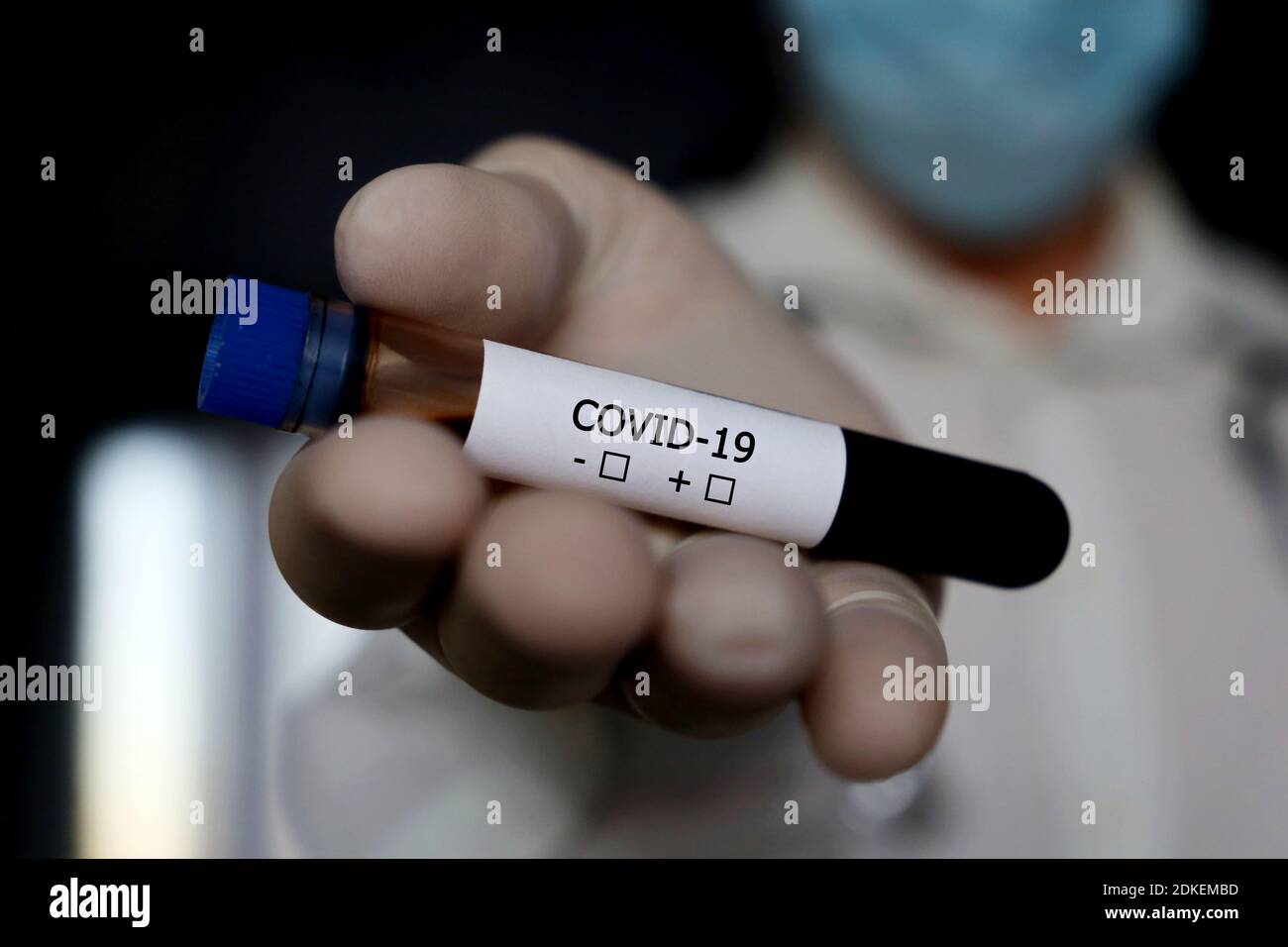 Doctor in mask holding test tube with covid-19 blood sample ...