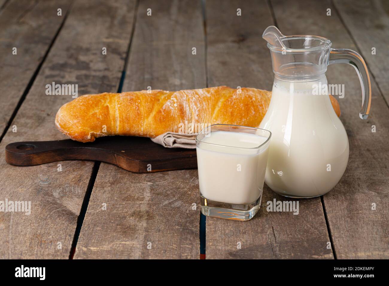 Cup of milk and bread loaf on wooden table Stock Photo - Alamy