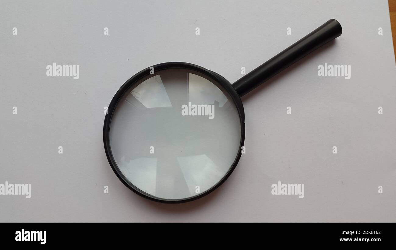 Magnifying glass placed over white sheet of paper with nice mild shadow ...