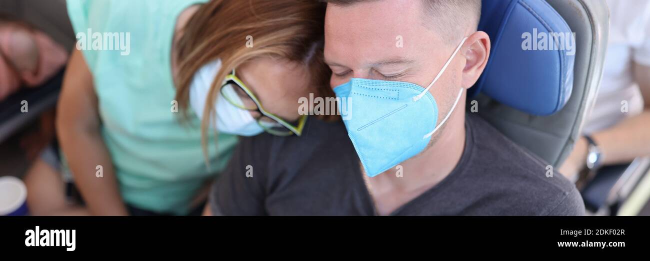 Man and woman in medical protective masks are sleeping in aircraft ...