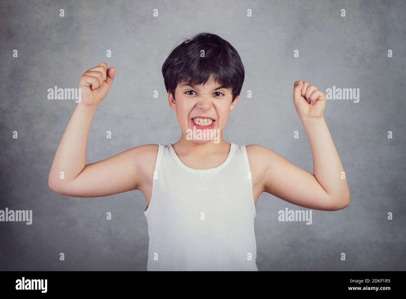 Portrait Of Boy Flexing Muscles While Standing Against Wall Stock Photo ...