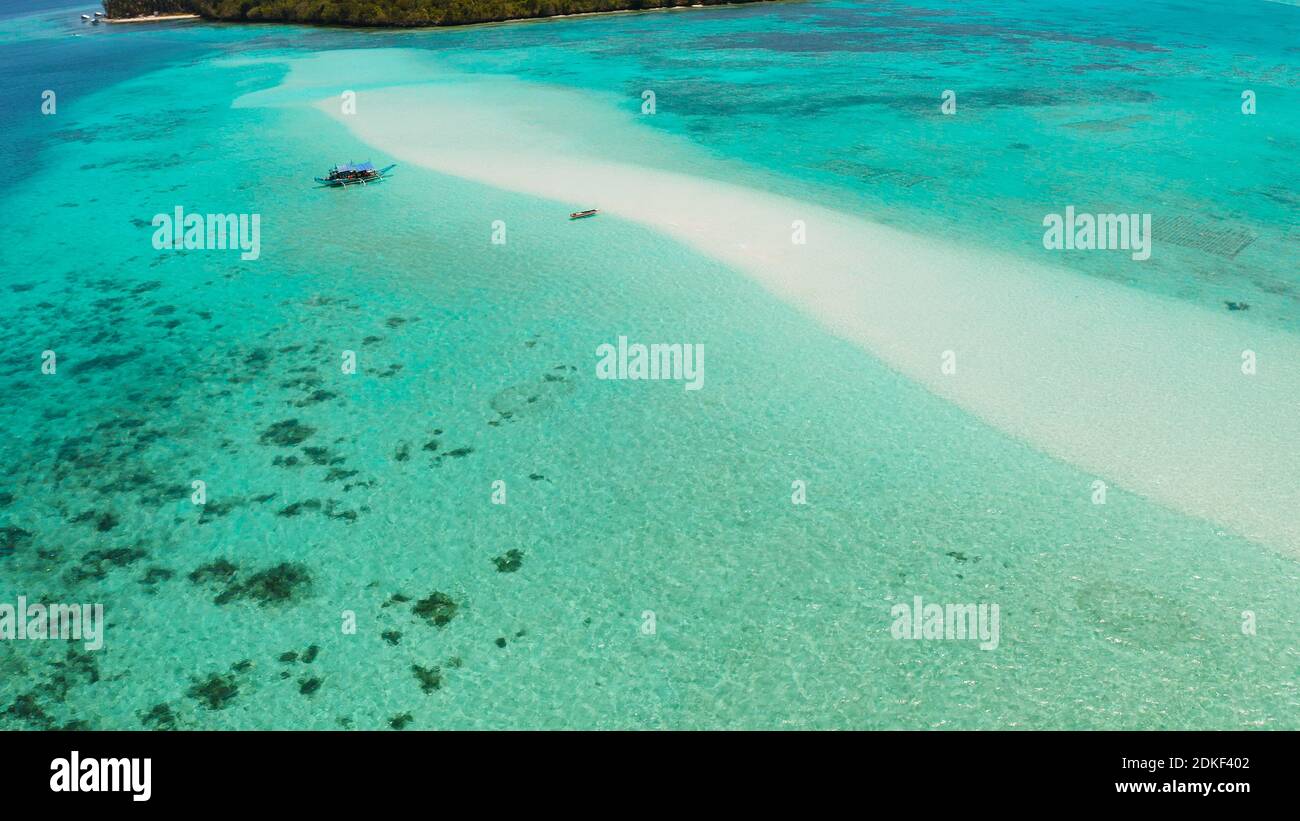 Sandy beach with tourists among turquoise waters and coral reefs ...