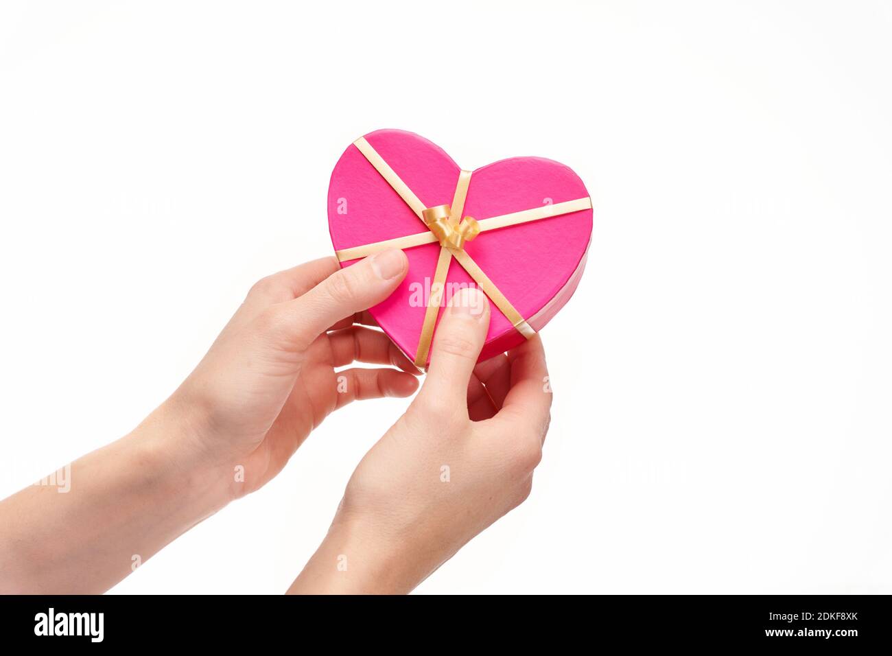 Hands handing over a heart shaped gift on white background, copy space ...