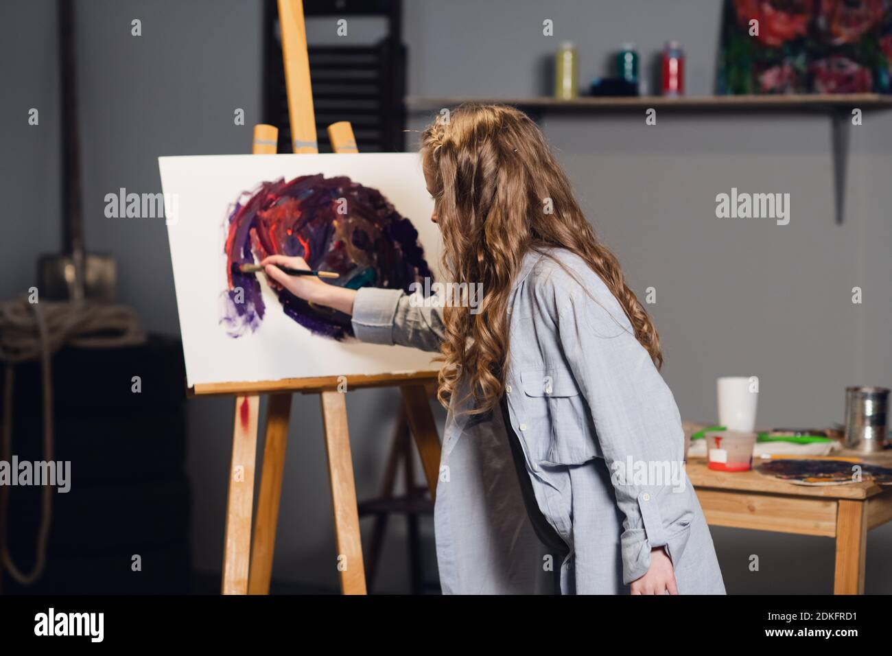 A young cute artist girl is learning to draw in an art workshop. Draws ...