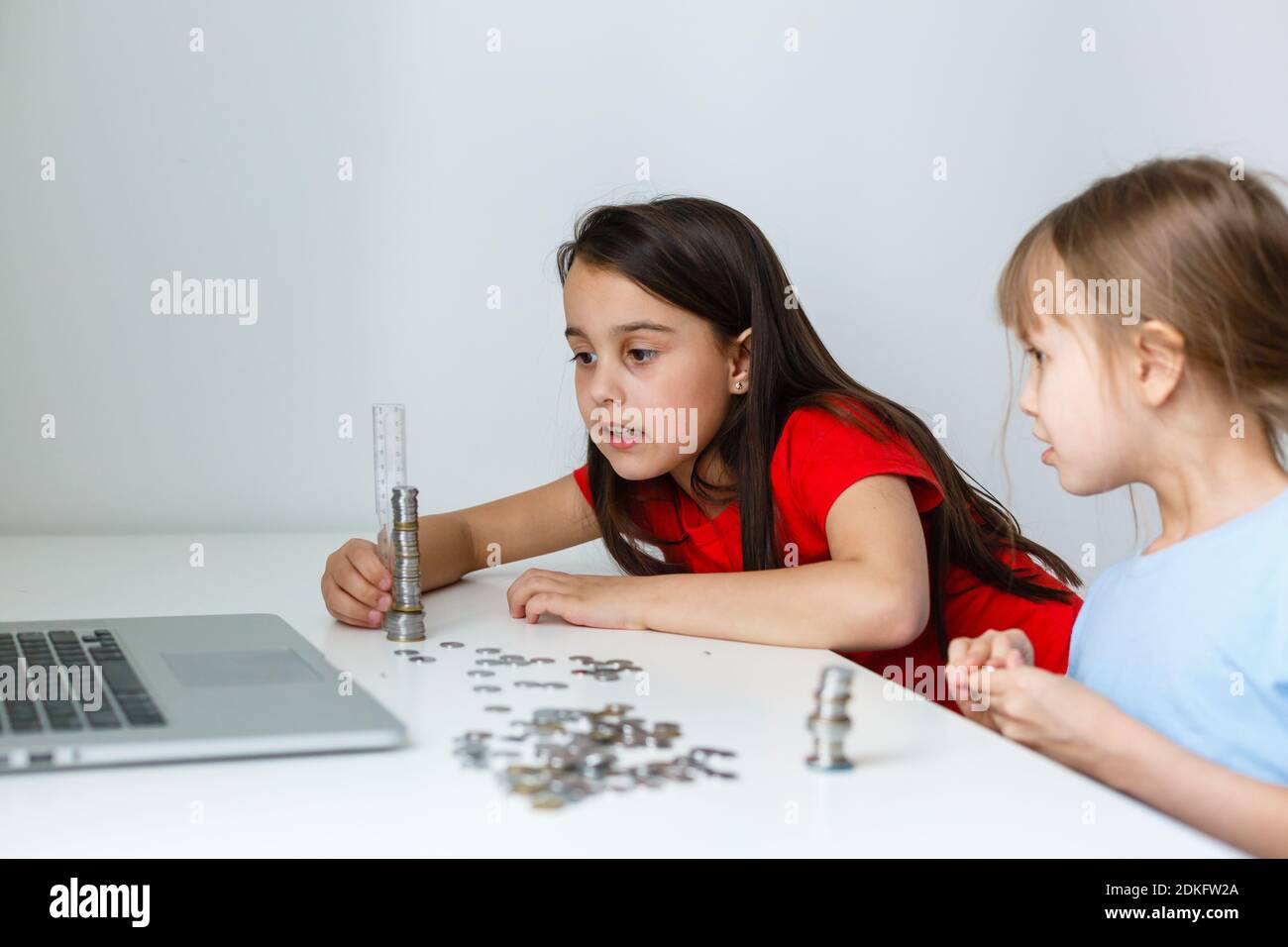portrait of little girls sitting at table and calculating money Stock ...