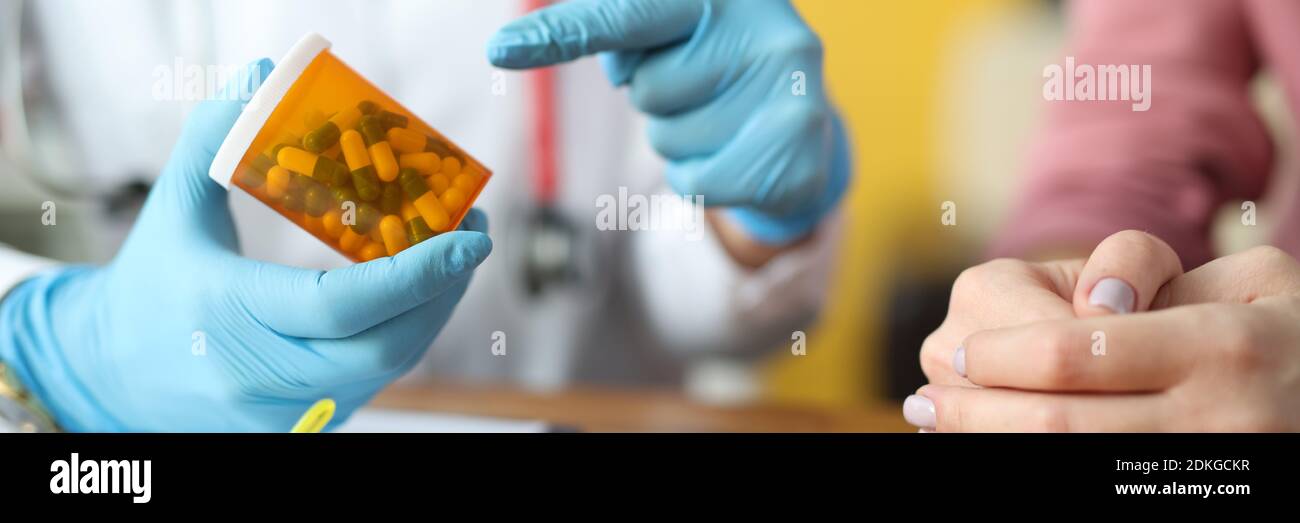 Doctor's hand points to pills next to patient sitting Stock Photo - Alamy