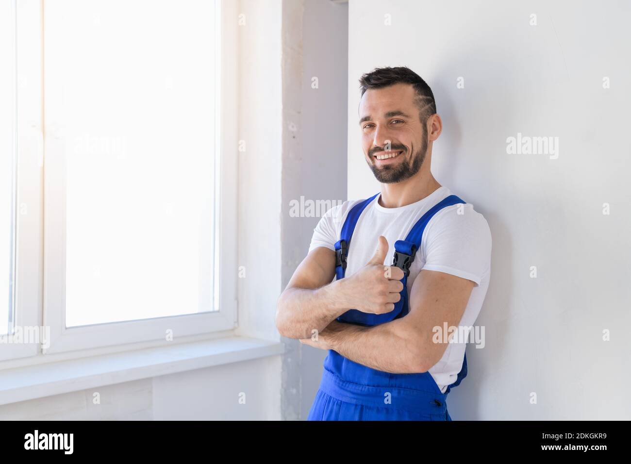 A craftsman in blue uniform stands against the wall and poses Stock ...