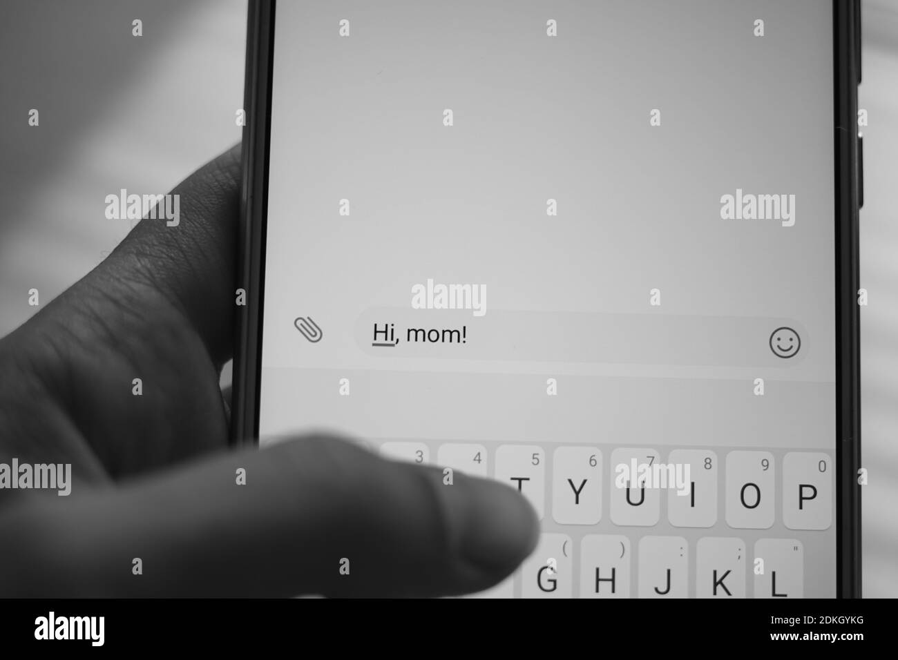 Fingers typing on a smartphone screen a message Hi, mom. BW photo Stock ...