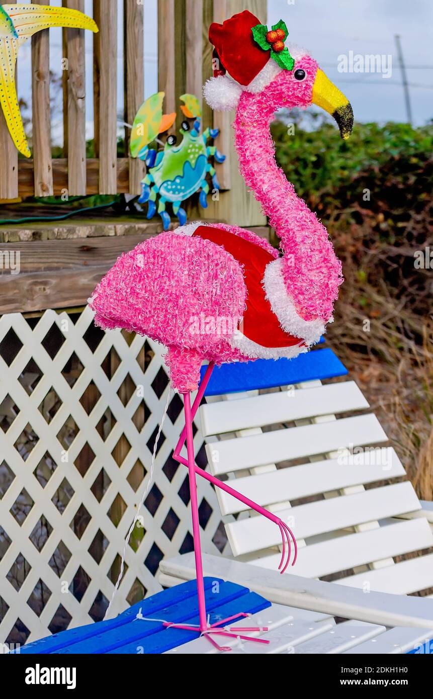 A pink flamingo statue wears a Santa Claus hat and Christmas outfit ...