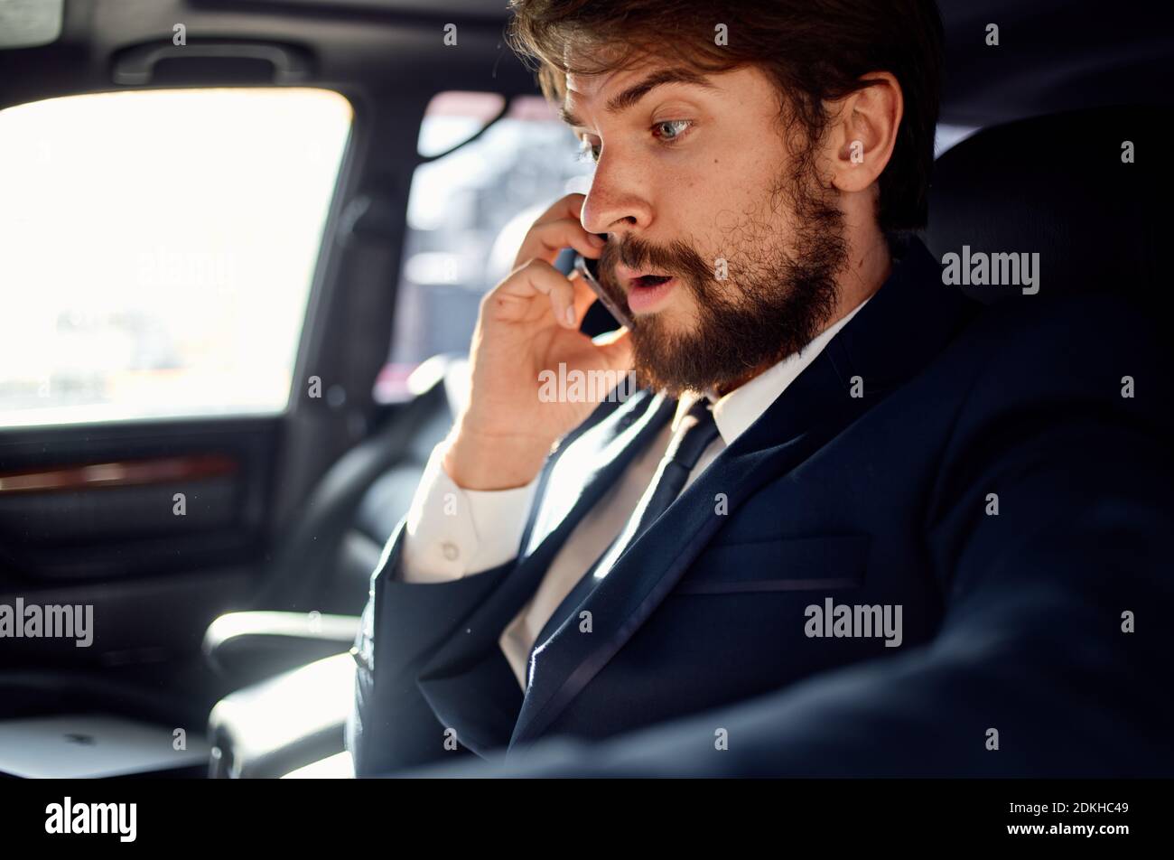 successful rich man in a suit talking on the phone while driving a ...