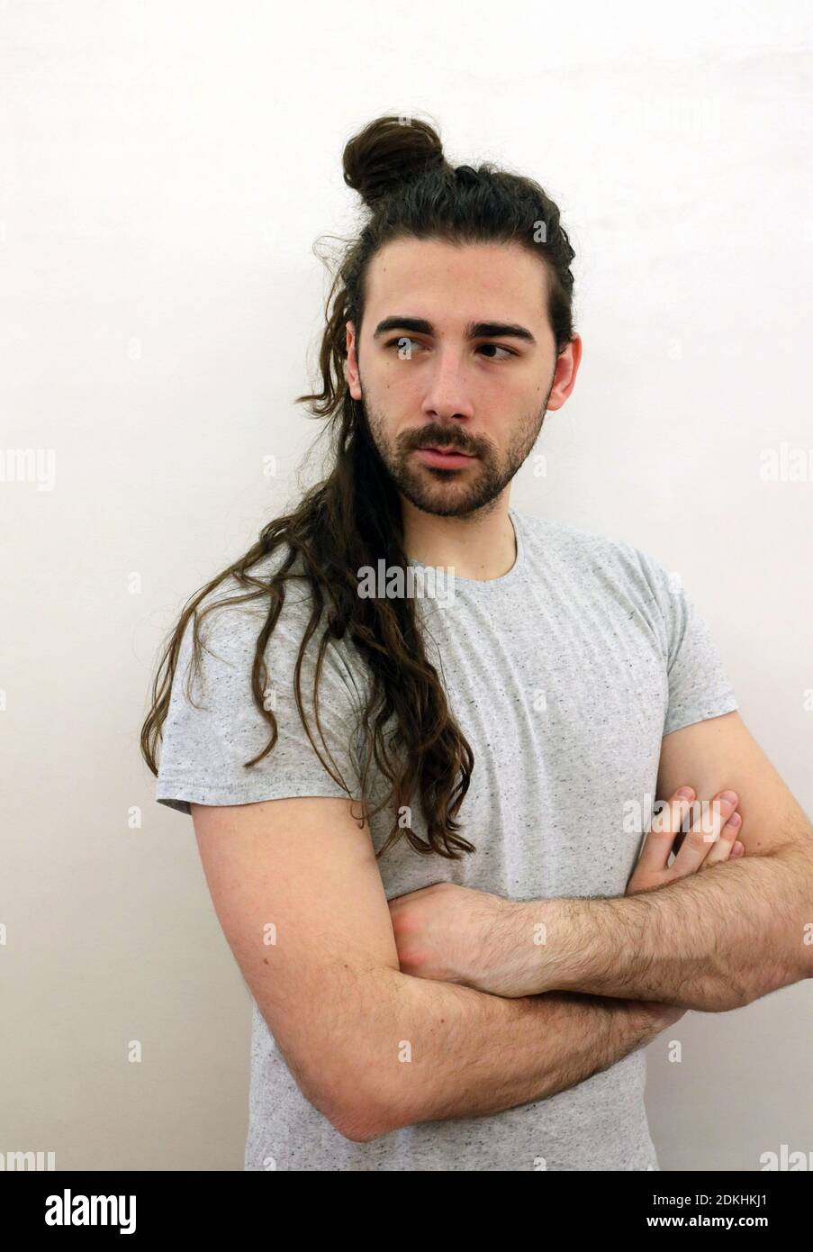 Attractive, young bearded male model with long hair posing indoors ...