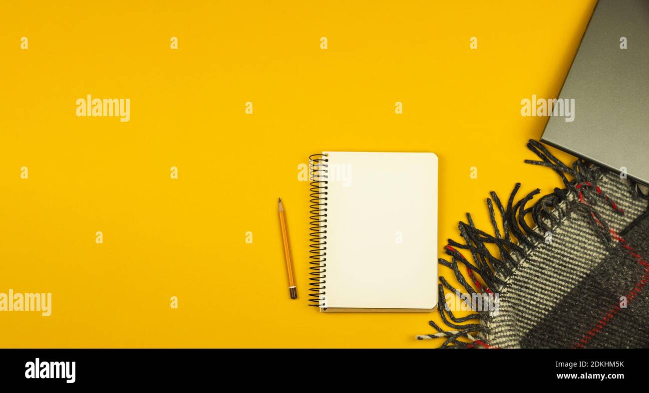 Simple cozy workplace with notepad and laptop, pencil and blanket on ...